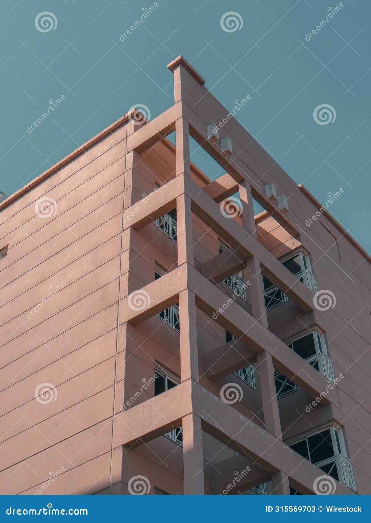 A Tan Colored Building with Windows and a Clock Mounted on the Side ...