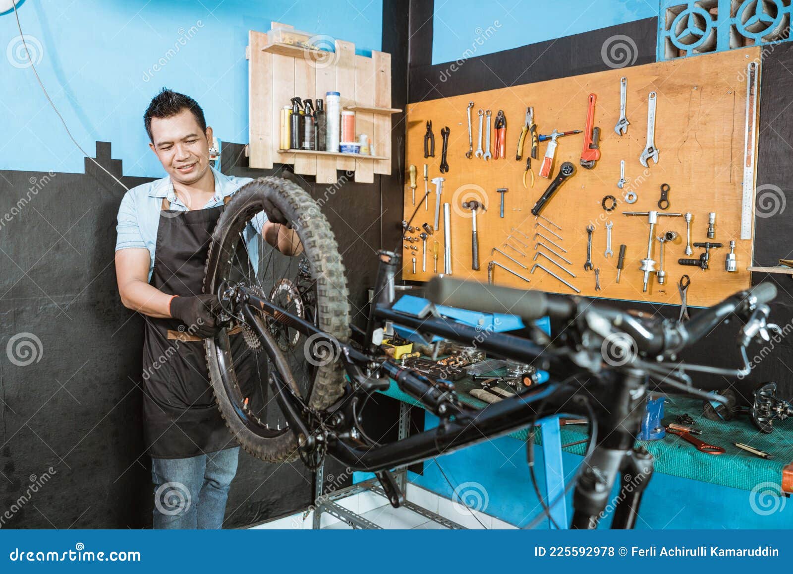 A Bicycle Mechanic in Apron Installs Wheels when Assembling a Bicycle ...