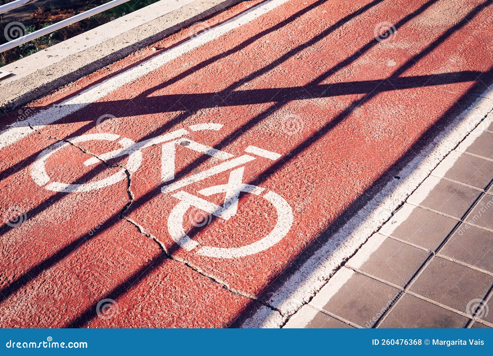 Bicycle Sign on a Red Bike Path Under a Shadow of a Fence Stock Photo ...