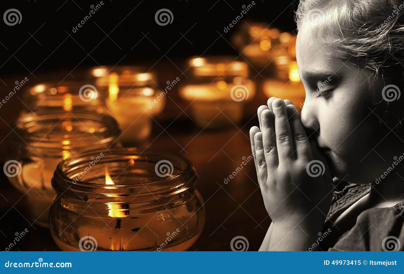 Biddend kind met kaarsen stock afbeelding. Image of handen - 49973415