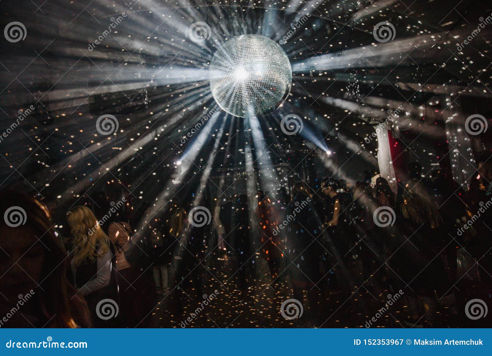 A Big Disco Ball is Hanging from the Ceiling. a Lot of People are ...