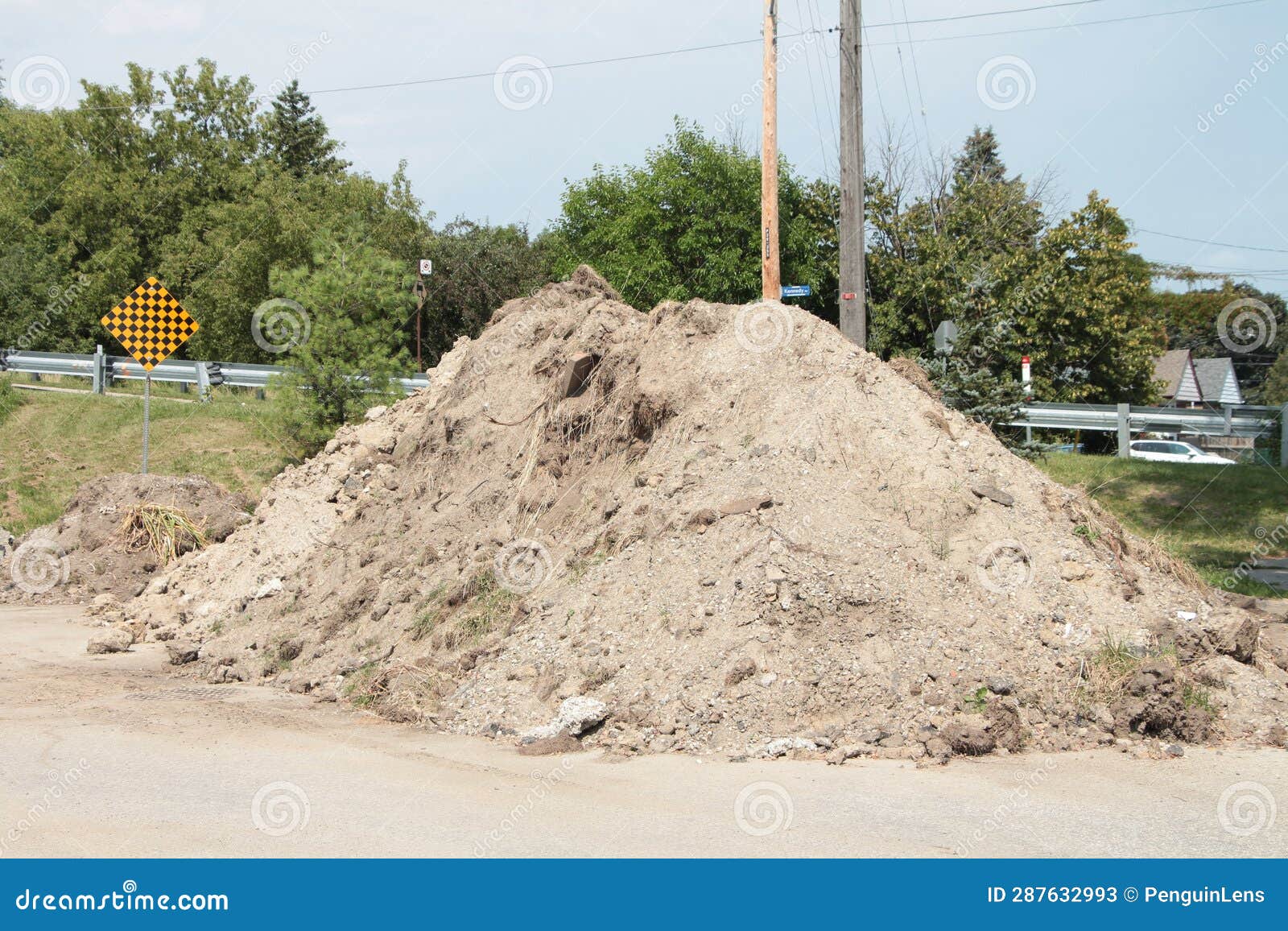 Big Pile of Dirt on Road with Bottom of Bridge and Trees Behind. P ...