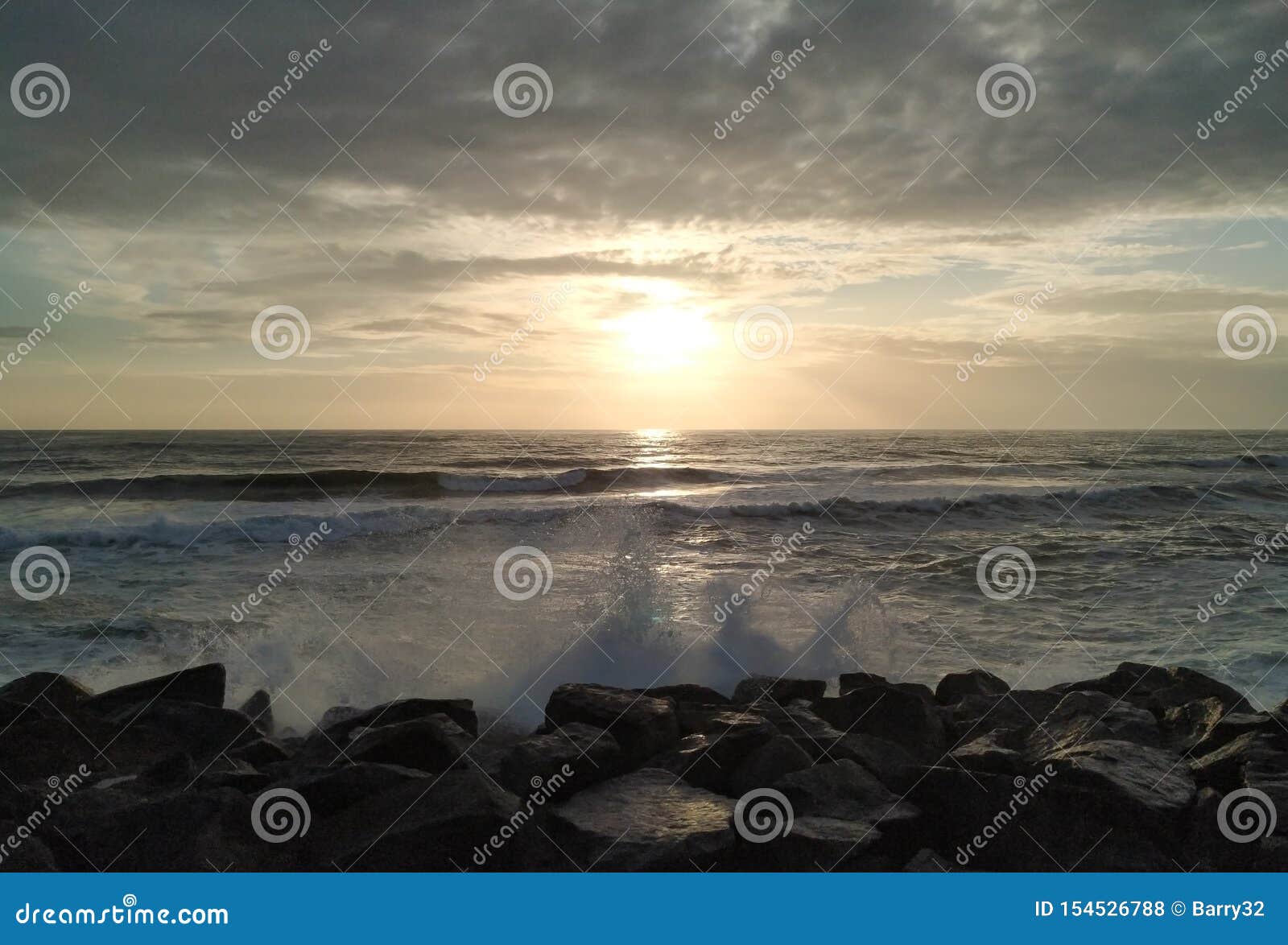 Big Waves Splash Over Rocks on Beach at Sunset with Dark Moody Clouds ...