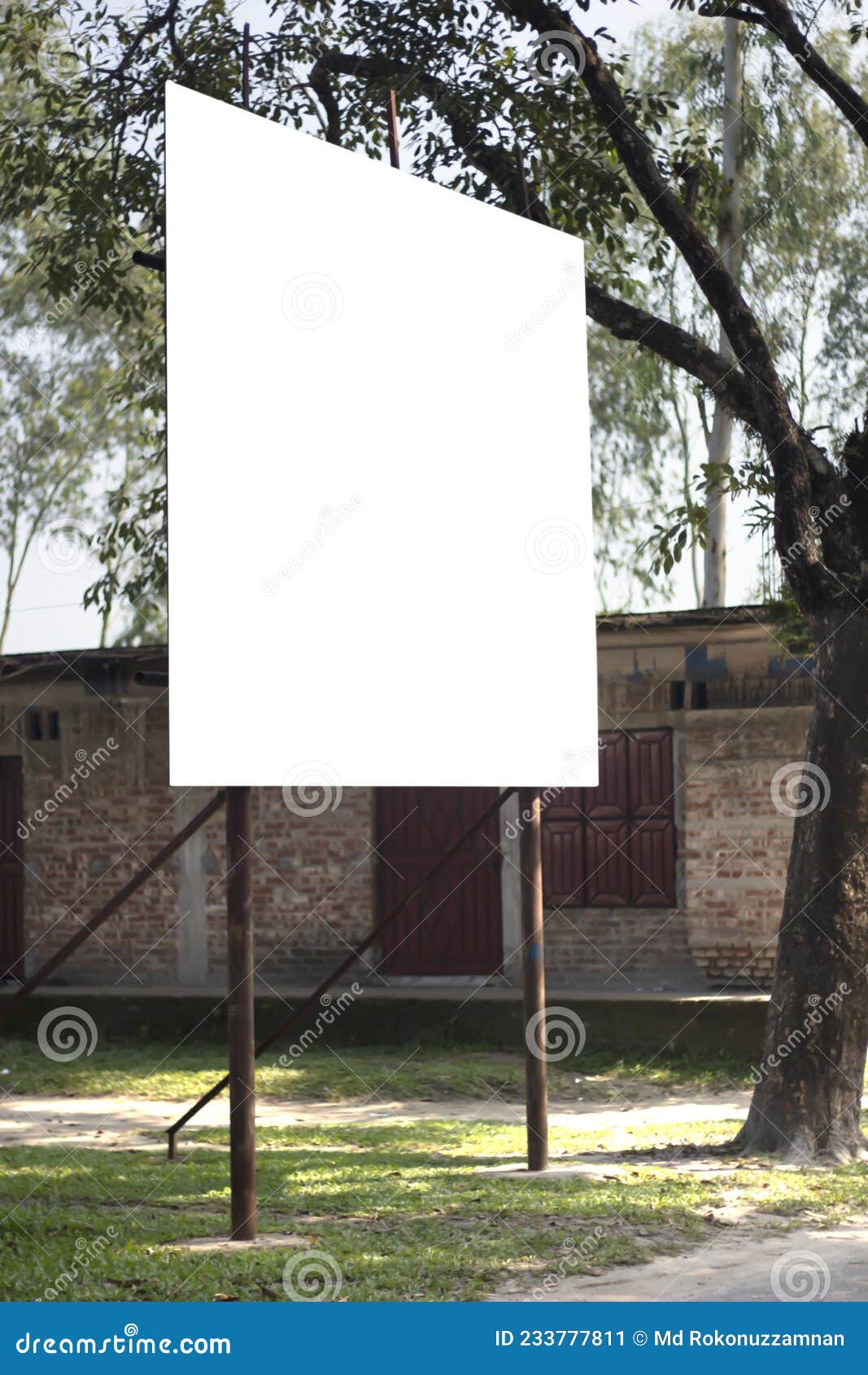 A Big White Signboard Attaches Two Iron Poles Under a Big Tree and the ...