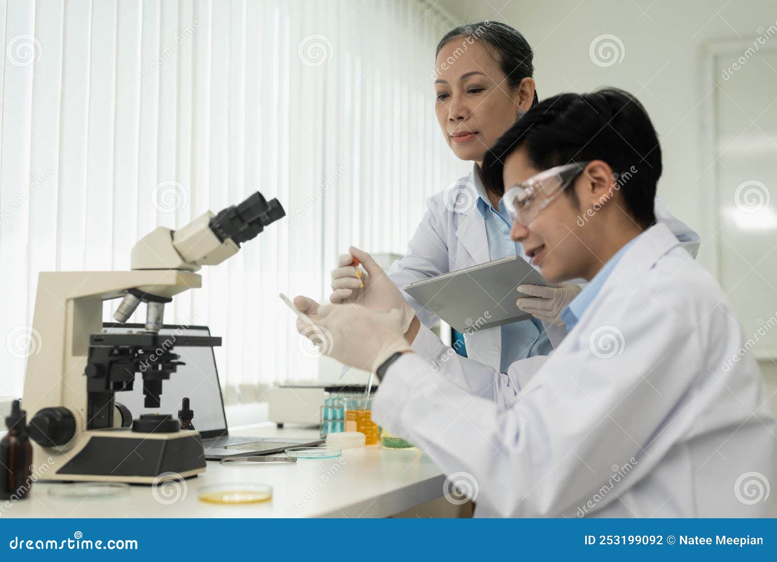 Biochemical Research Scientist Team Working with Microscope for Vaccine ...