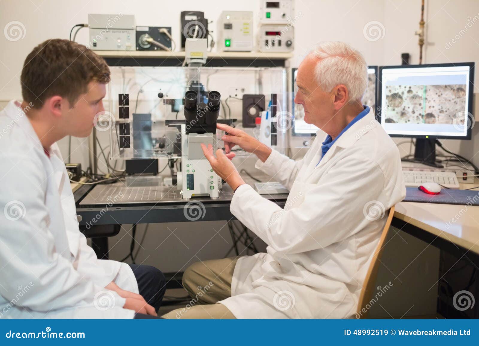 Biochemist Using Large Microscope and Computer with Student Stock Image ...