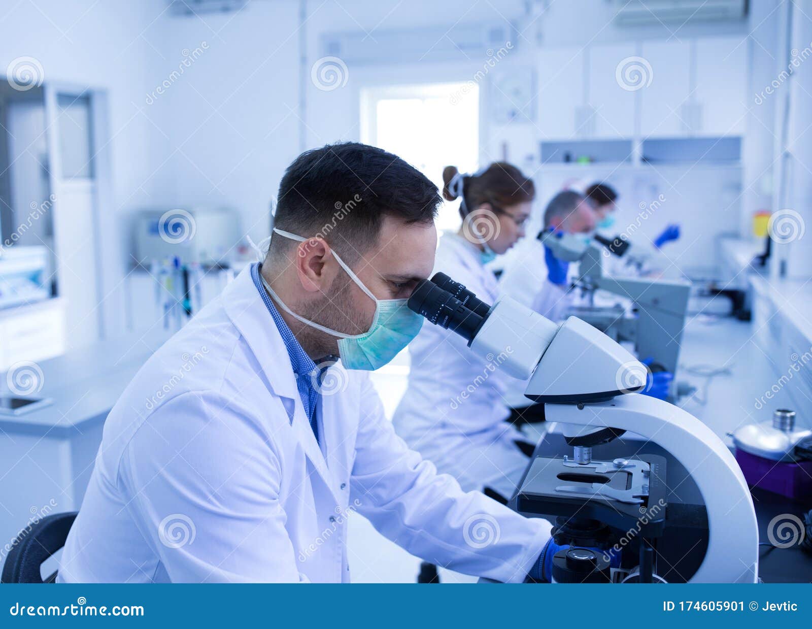 Biologists Looking through Microscope in Laboratory Stock Image - Image ...