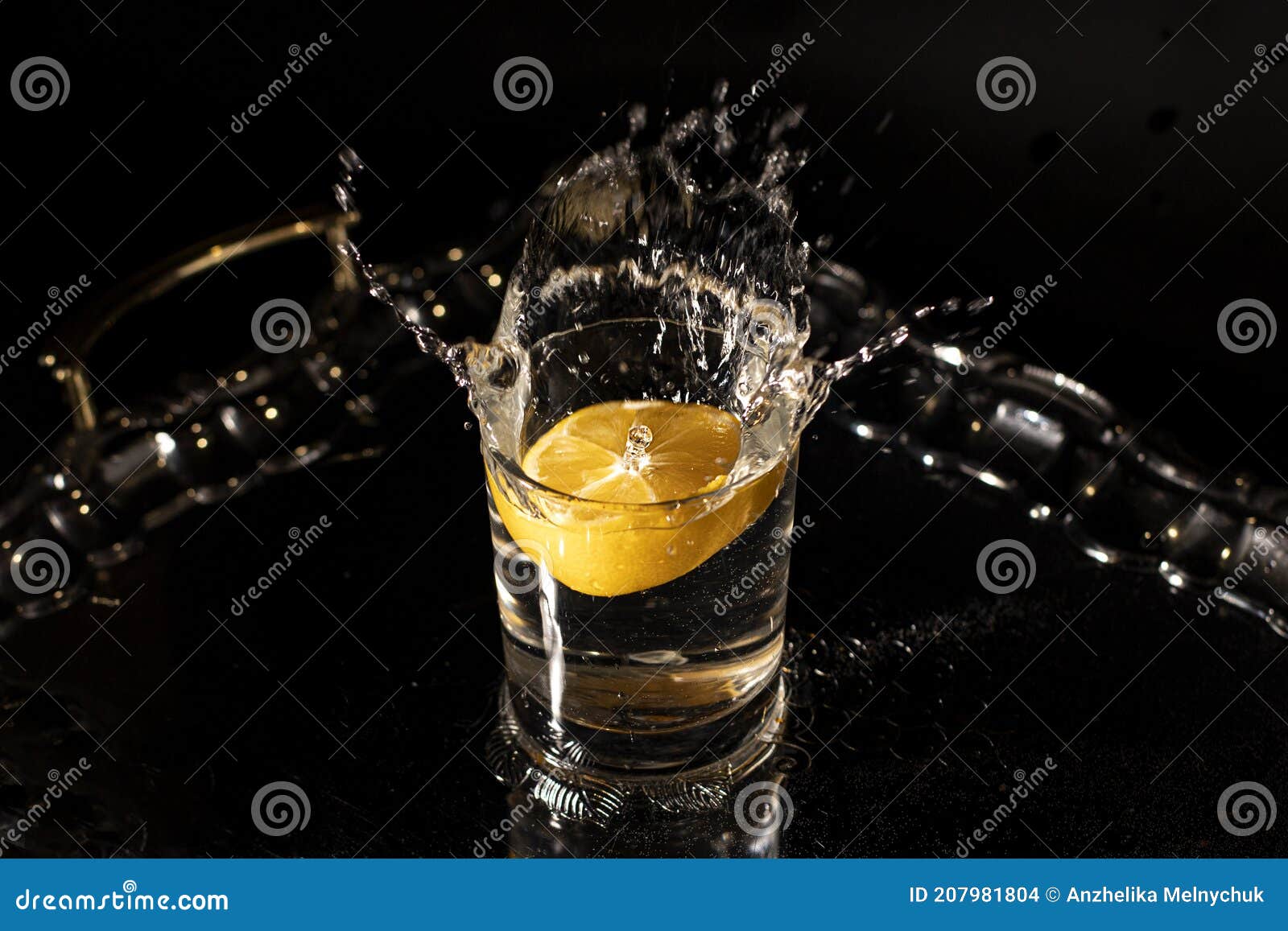 On a Black Background Lemon Falls into a Glass and Splashes of Water ...