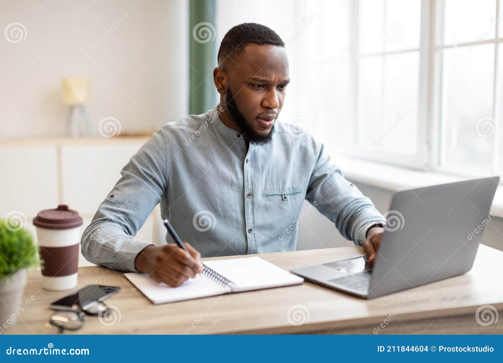 Black Businessman Working Taking Notes and Using Laptop at Workplace ...