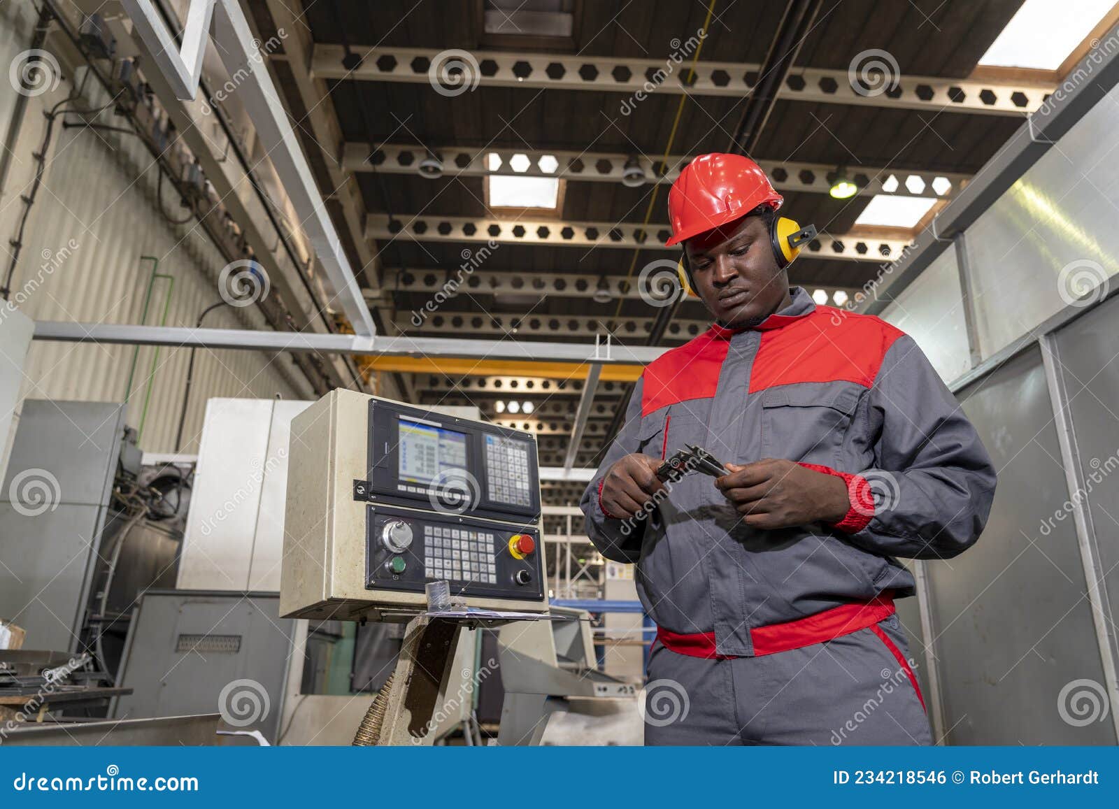 Black CNC Machine Operator in Protective Workwear Checking Measurements ...
