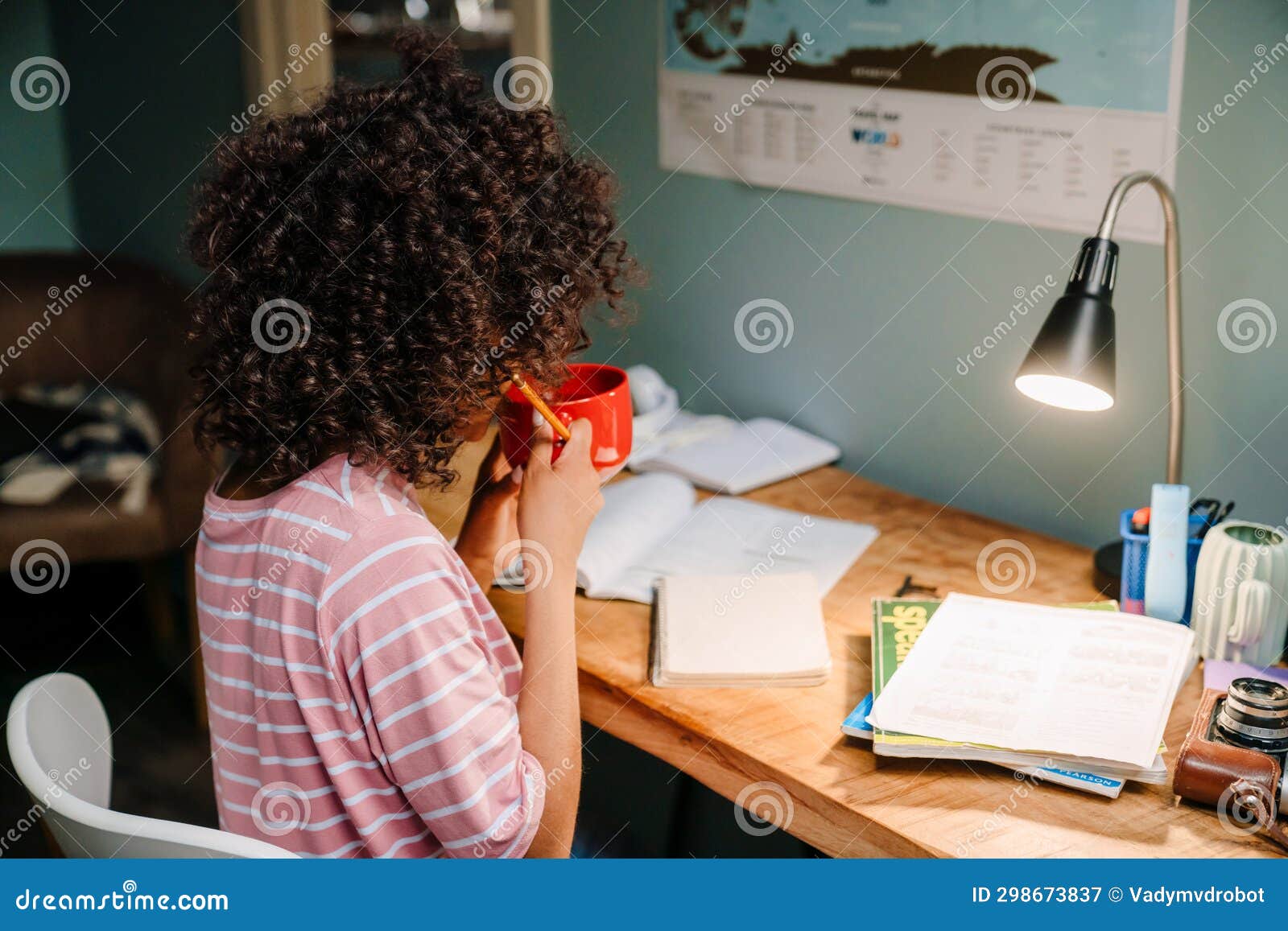 Black Curly Girl Drinking Tea Doing Homework while Sitting at Table ...