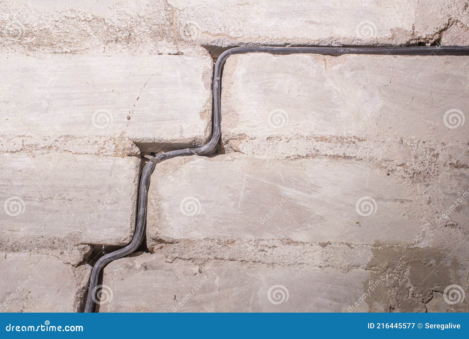 A Black Electrical Cable Runs between the White Bricks on the Wall ...