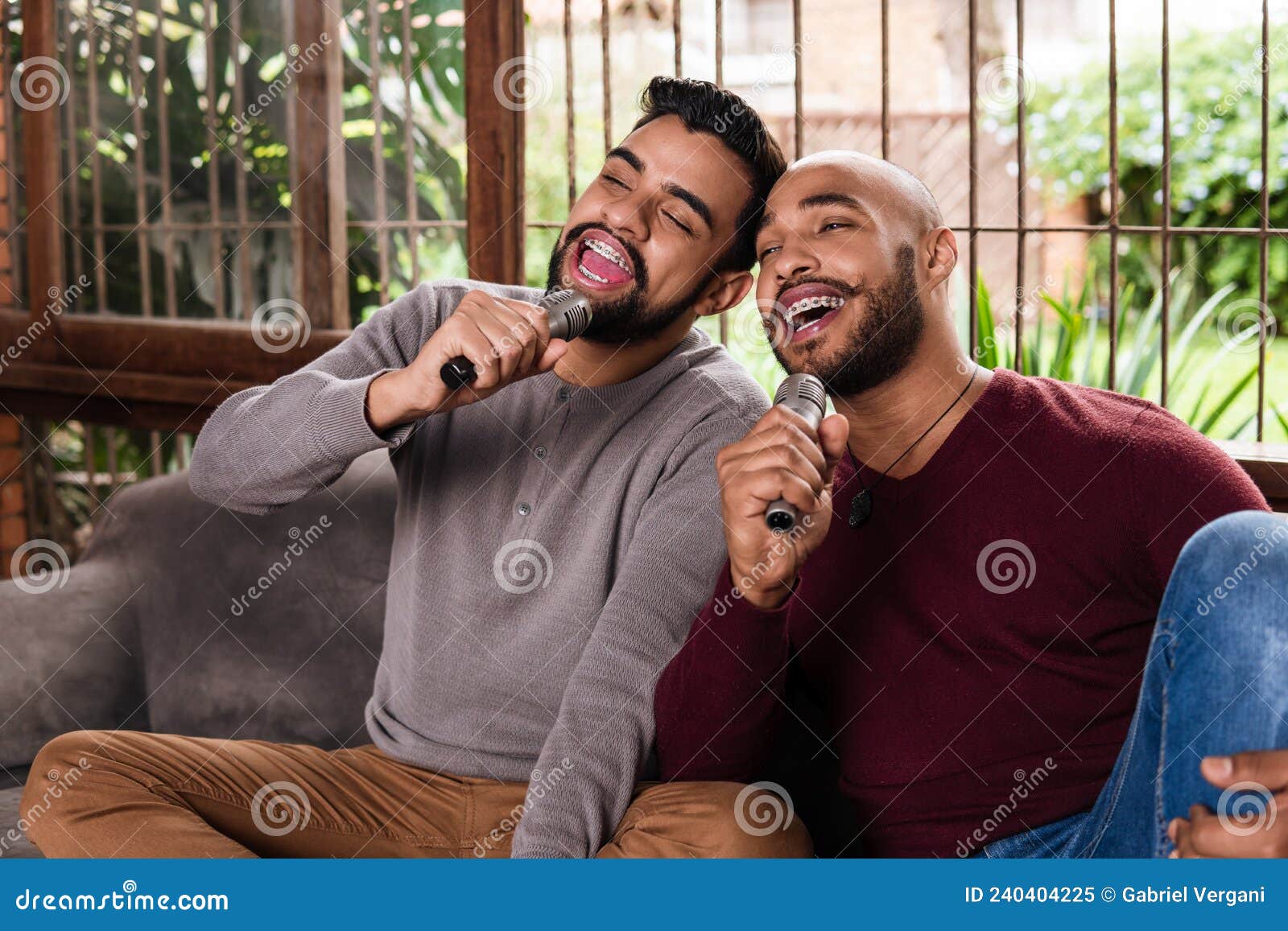Gay Couple Singing Together Karaoke Style In The Couch Stock Image