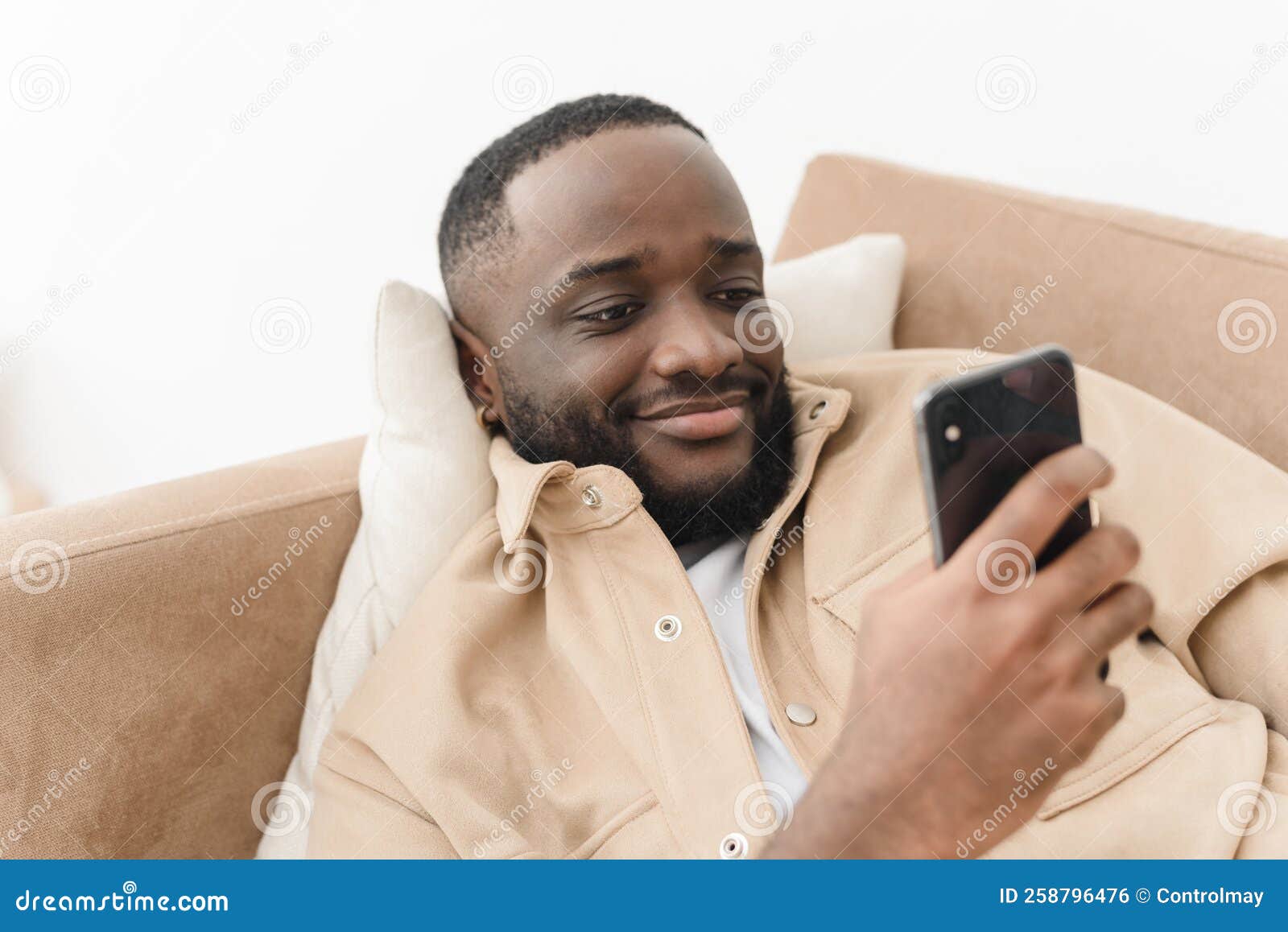Black Guy Using Smartphone, Browsing Internet and Texting while Lying ...