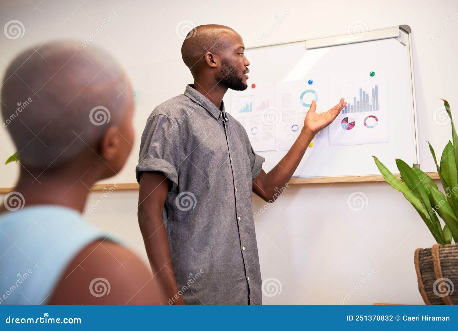 A Black Man Gives a Presentation in the Workplace with Graphs Stock ...
