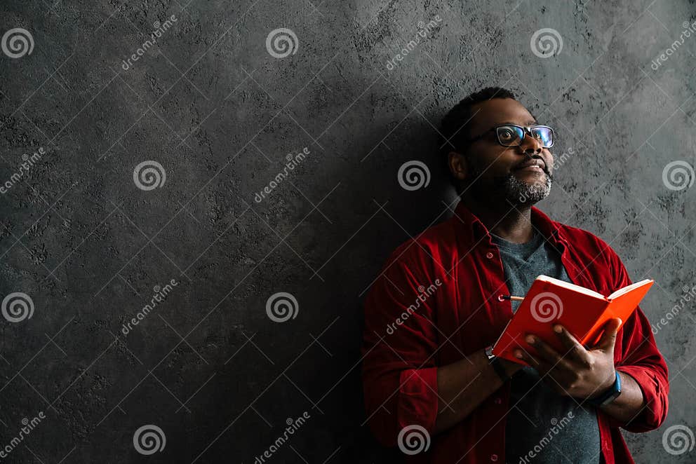 Black Man Writing Down Notes while Leaning on Concrete Wall Stock Image ...