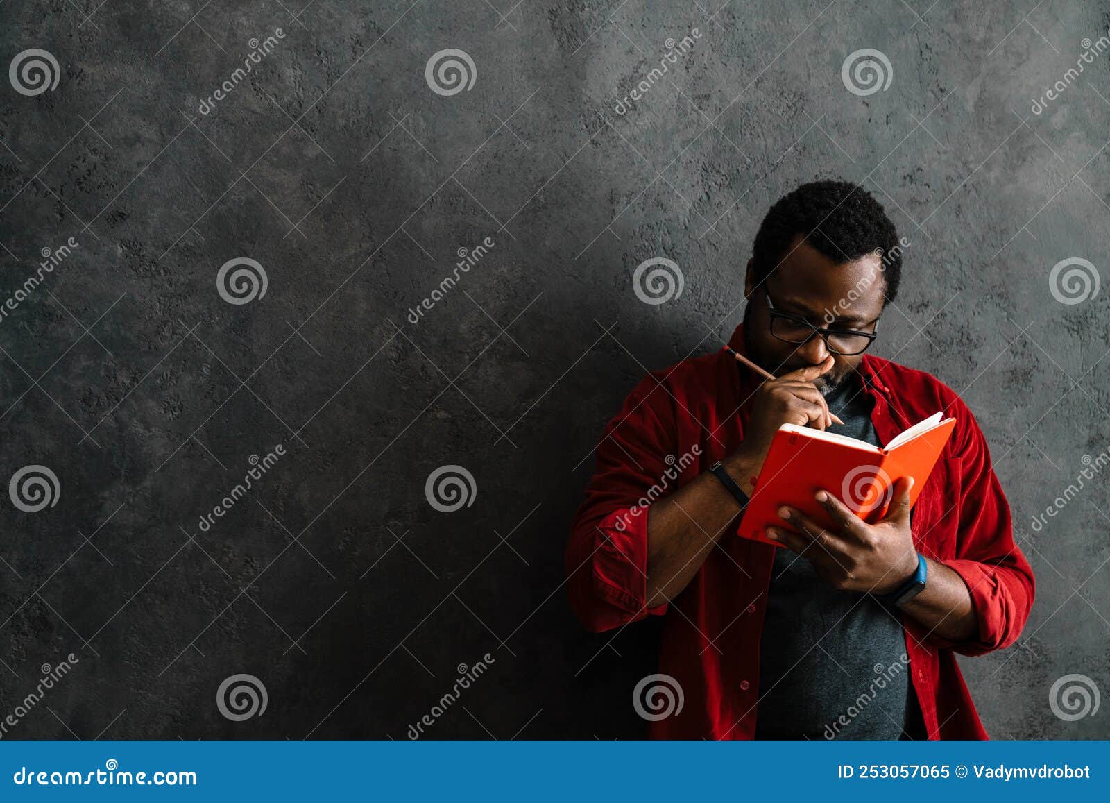 Black Man Writing Down Notes while Leaning on Concrete Wall Stock Image ...