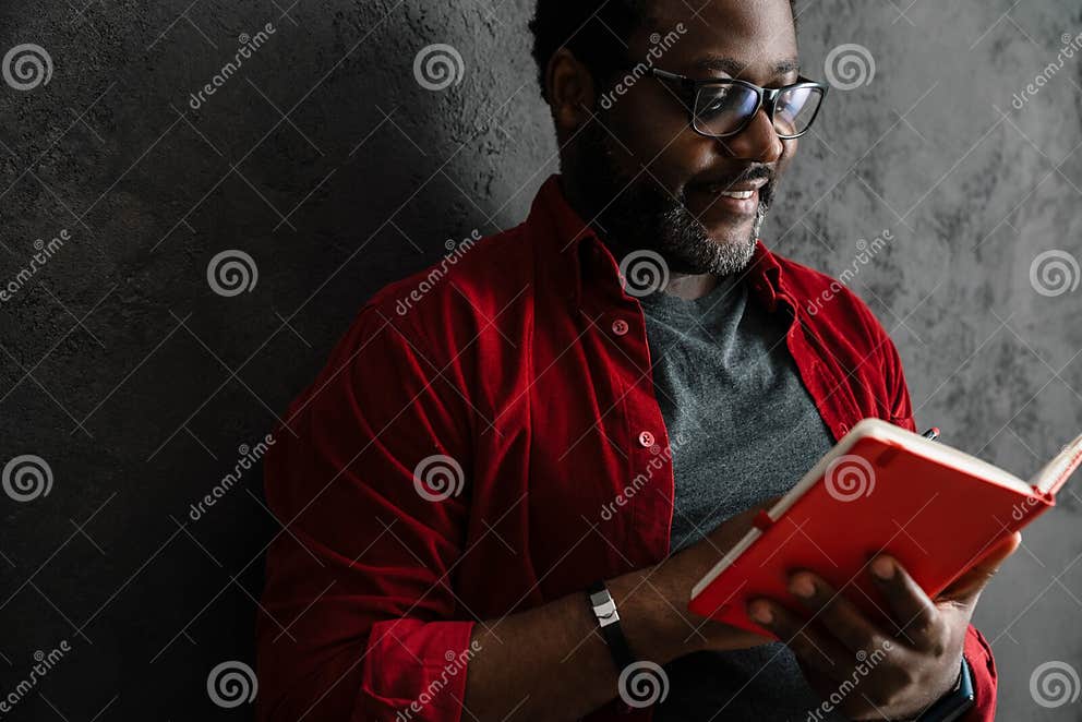 Black Man Writing Down Notes while Leaning on Concrete Wall Stock Photo ...
