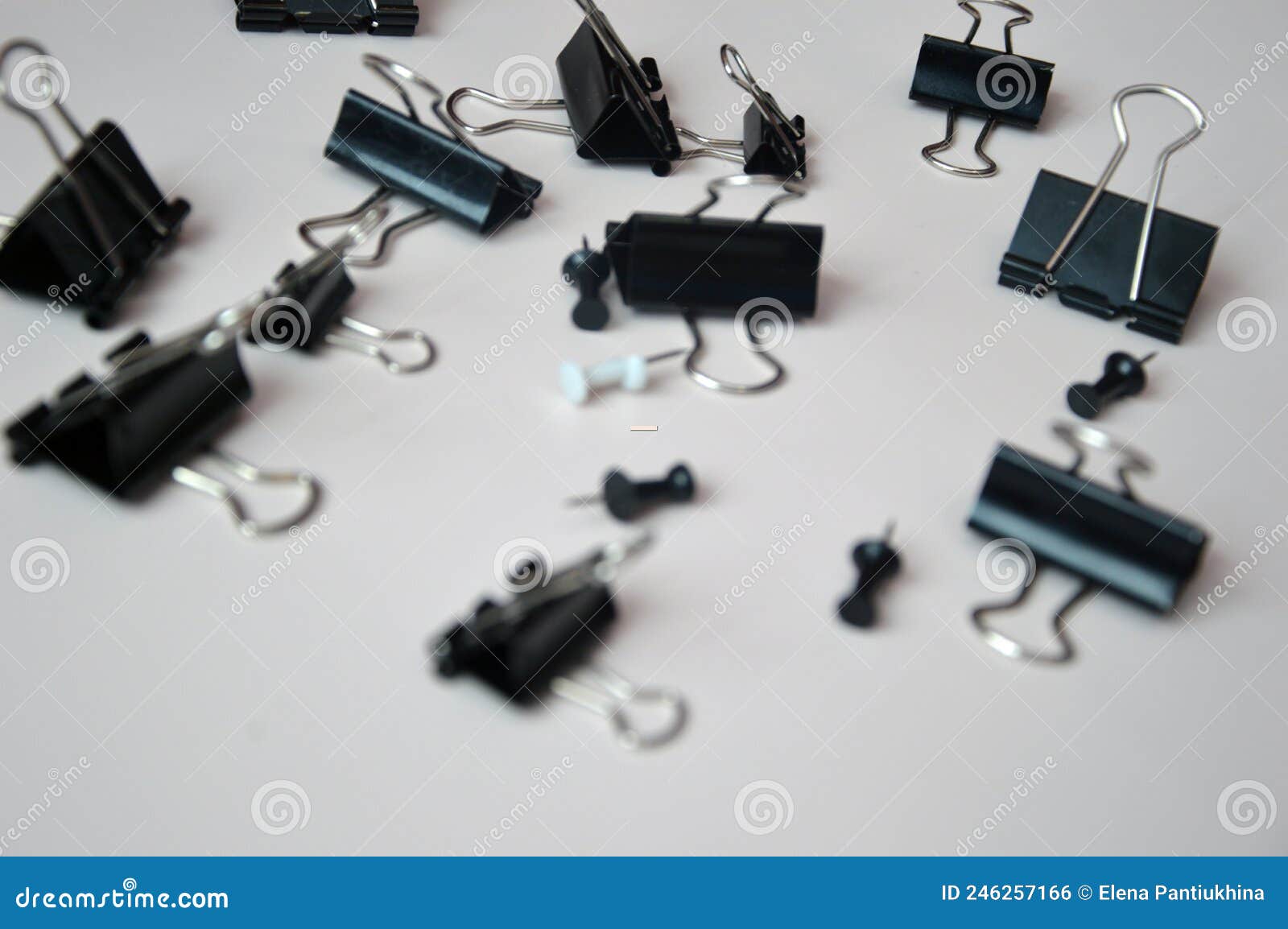 Black Push Pins and Document Clips and Buttons Scattered on a White ...
