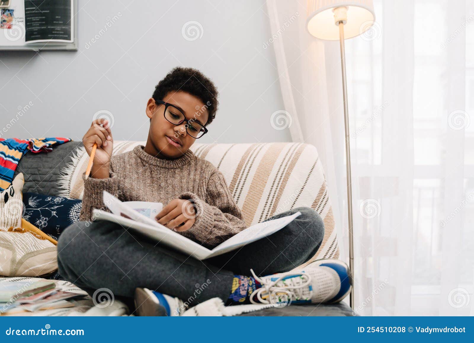 Black Puzzled Boy Doing Homework while Sitting on Sofa Stock Photo ...