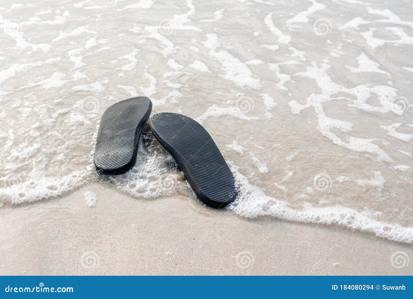 Black Slippers on the Beach Touched by Waves from the Sea Stock Photo ...