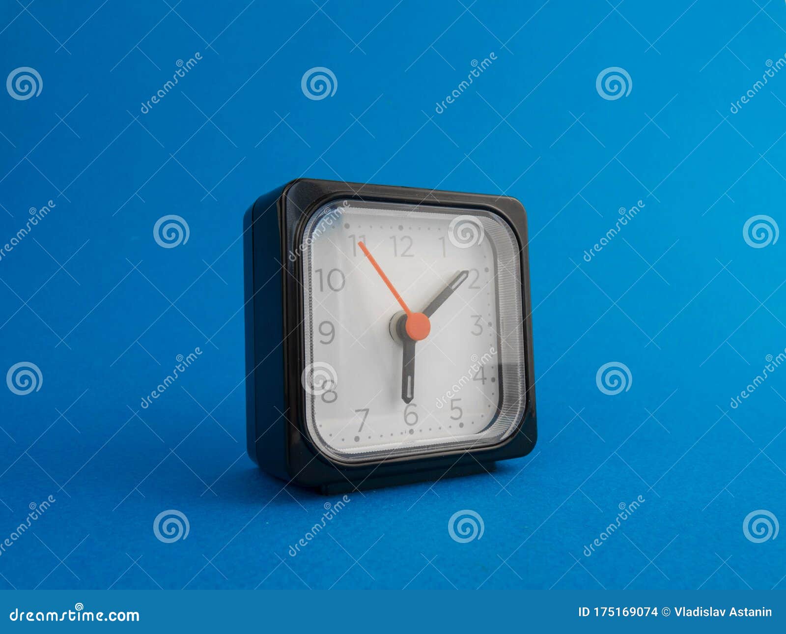 Black Table Clock with a Red Arrow Standing Sideways on a Blue ...