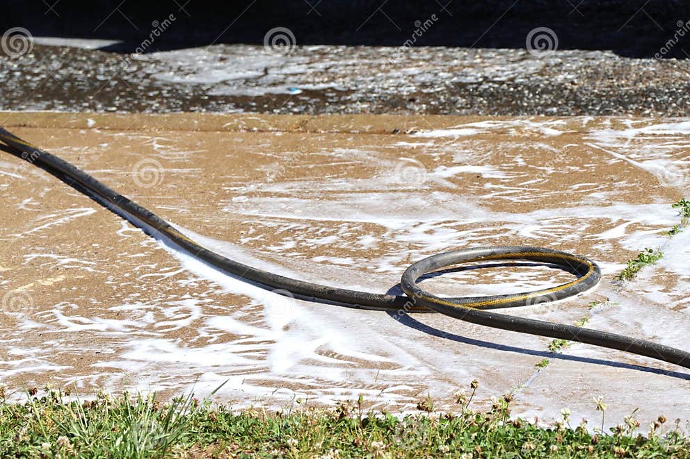Black Water Hose Loop on Cement Sidewalk with Soapy Water Stock Photo ...