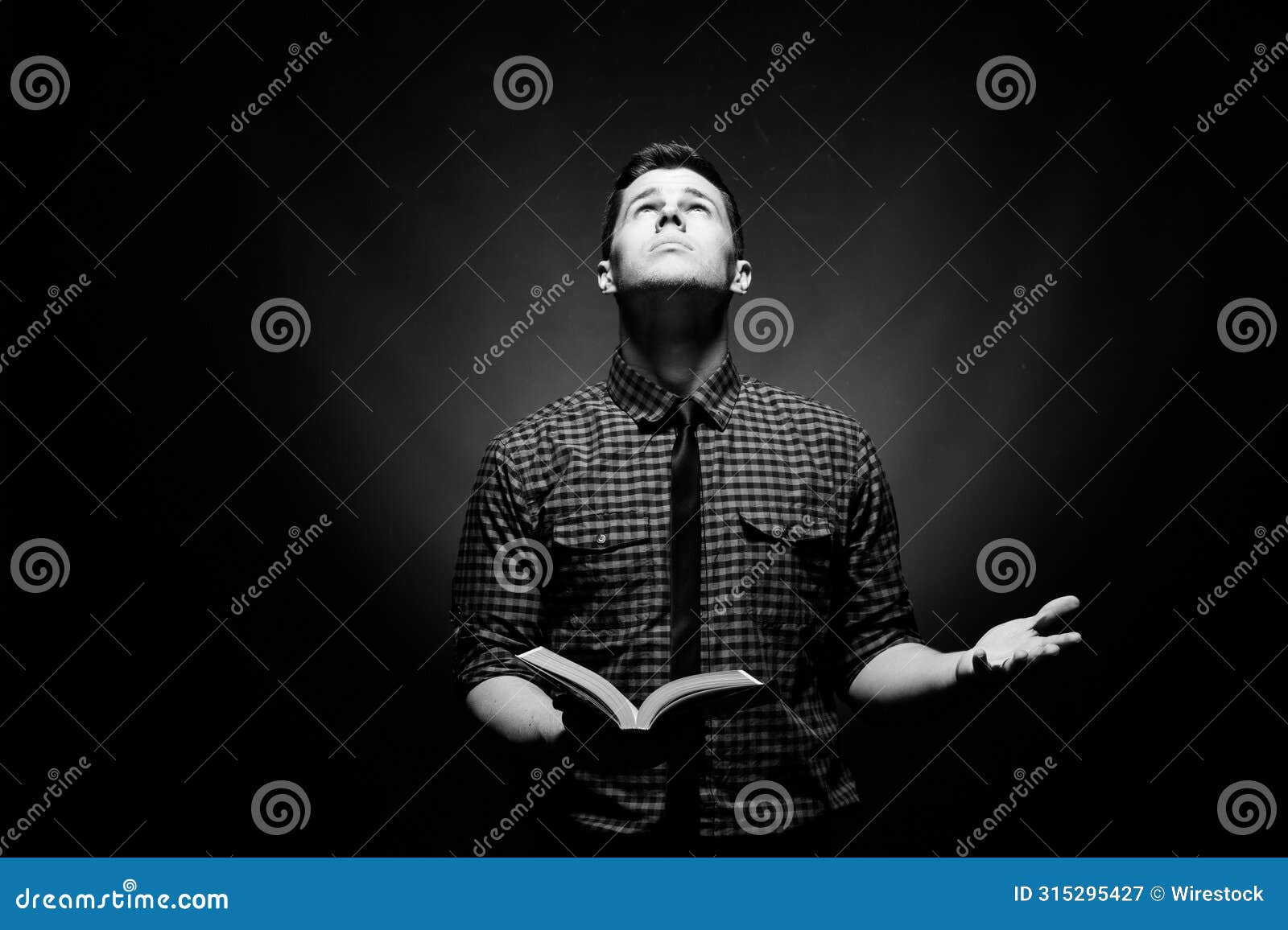 Black and White Image of a Man Looking Up with a Book in One Hand and a ...