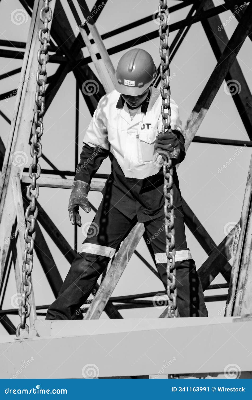 Black and White Shot of a Construction Worker Handling Chains on a High ...