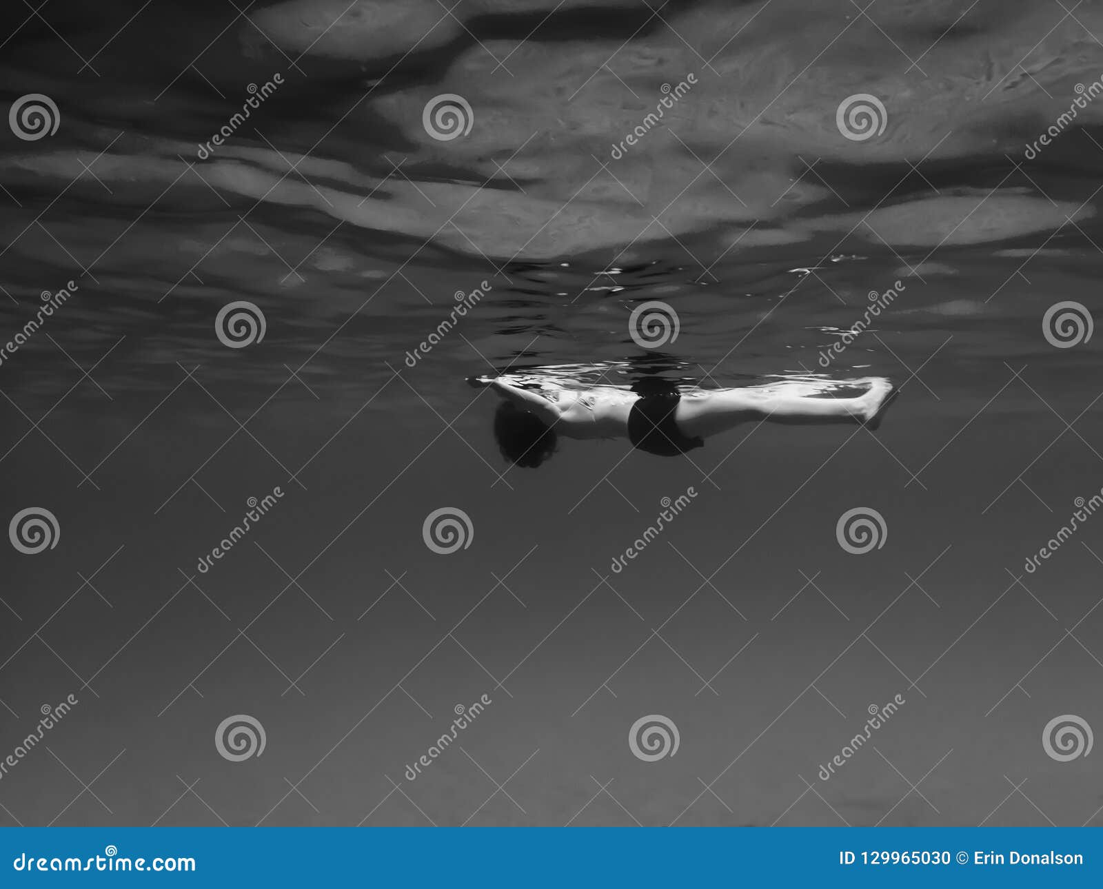 Black and White Woman Floating on Surface of Ocean from Underwater Low ...