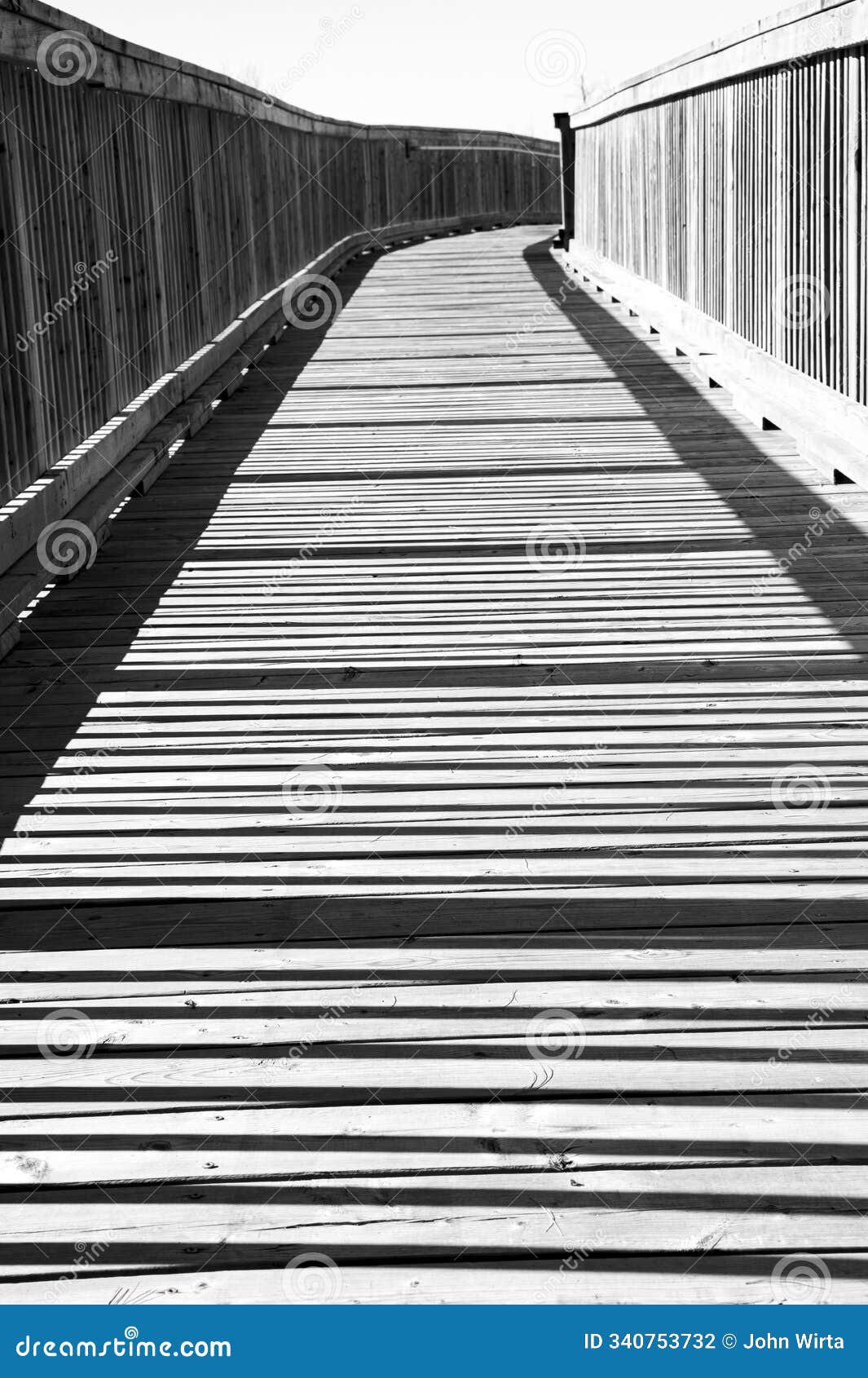 Black and White Wooden Walkway with Shadows from the Railing Creating a ...