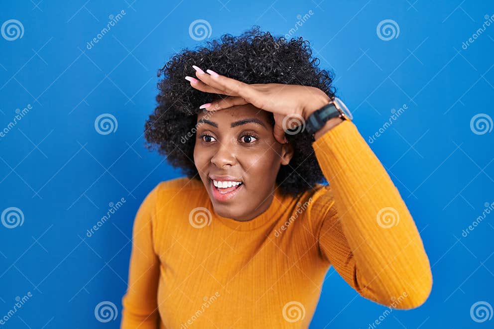 Black Woman With Curly Hair Standing Over Blue Background Very Happy