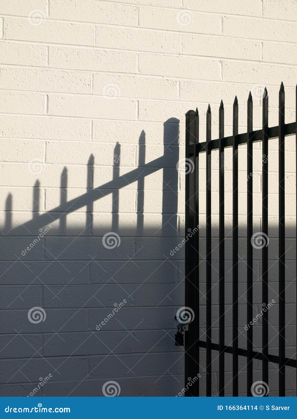 Black Wrought Iron Gate Casting Its Shadow On A White Brick Wall Stock ...