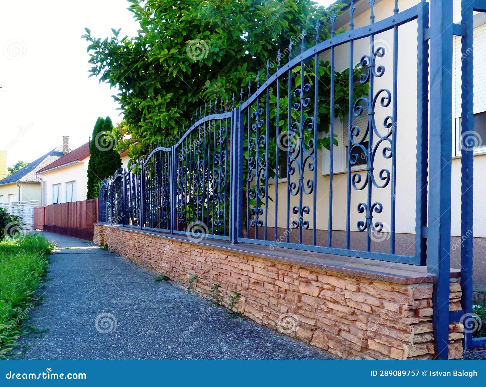 Wrought Iron Fence between Square Stone Piers and Solid Stone Base ...