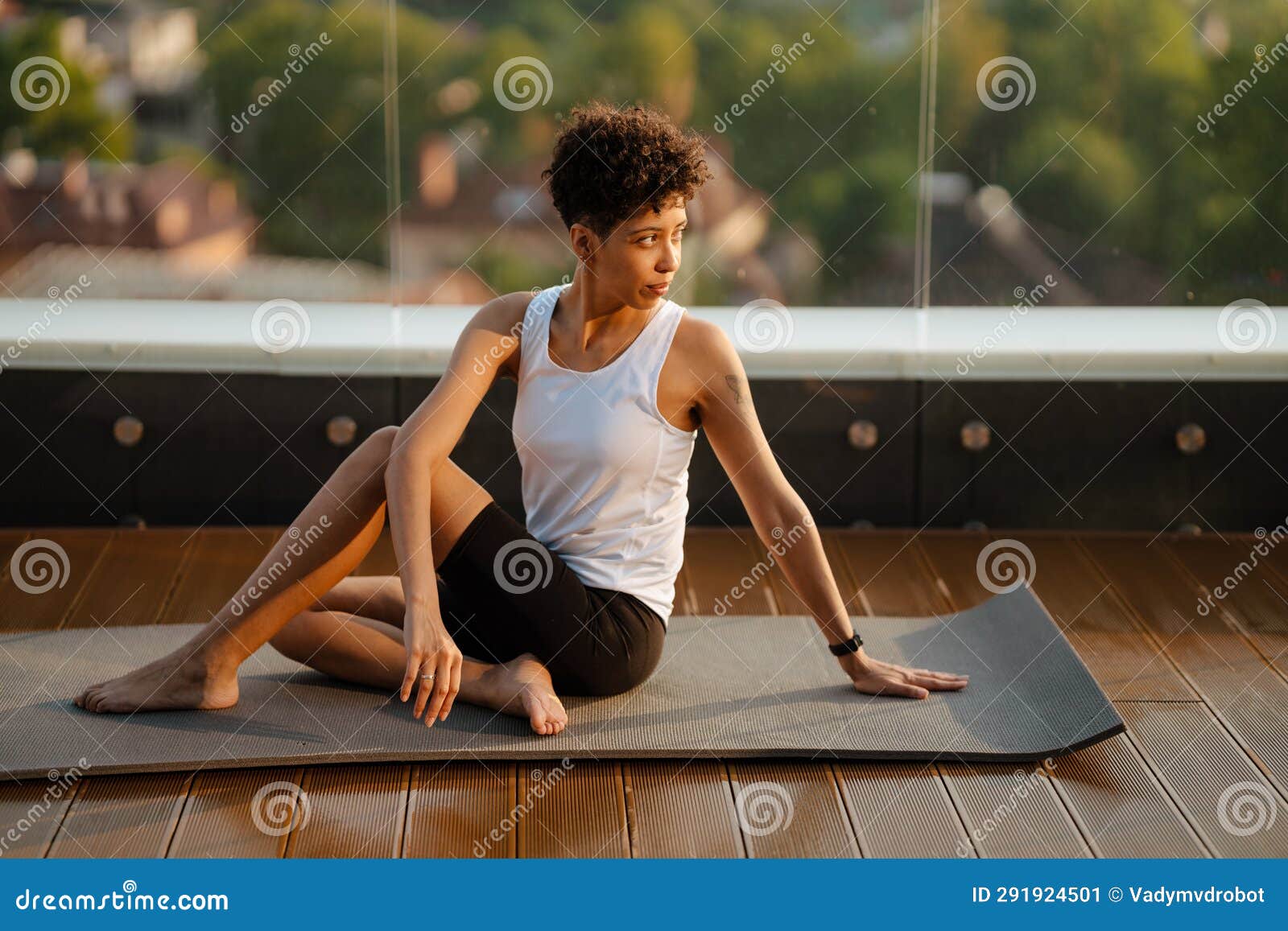 Black Young Woman Doing Exercise During Yoga Practice On Rooftop Stock
