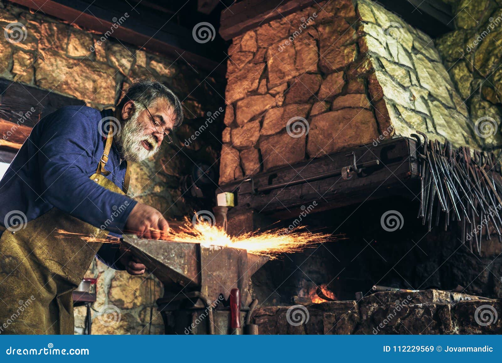 Blacksmith Manually Forging The Molten Metal On The Anvil In Smithy ...