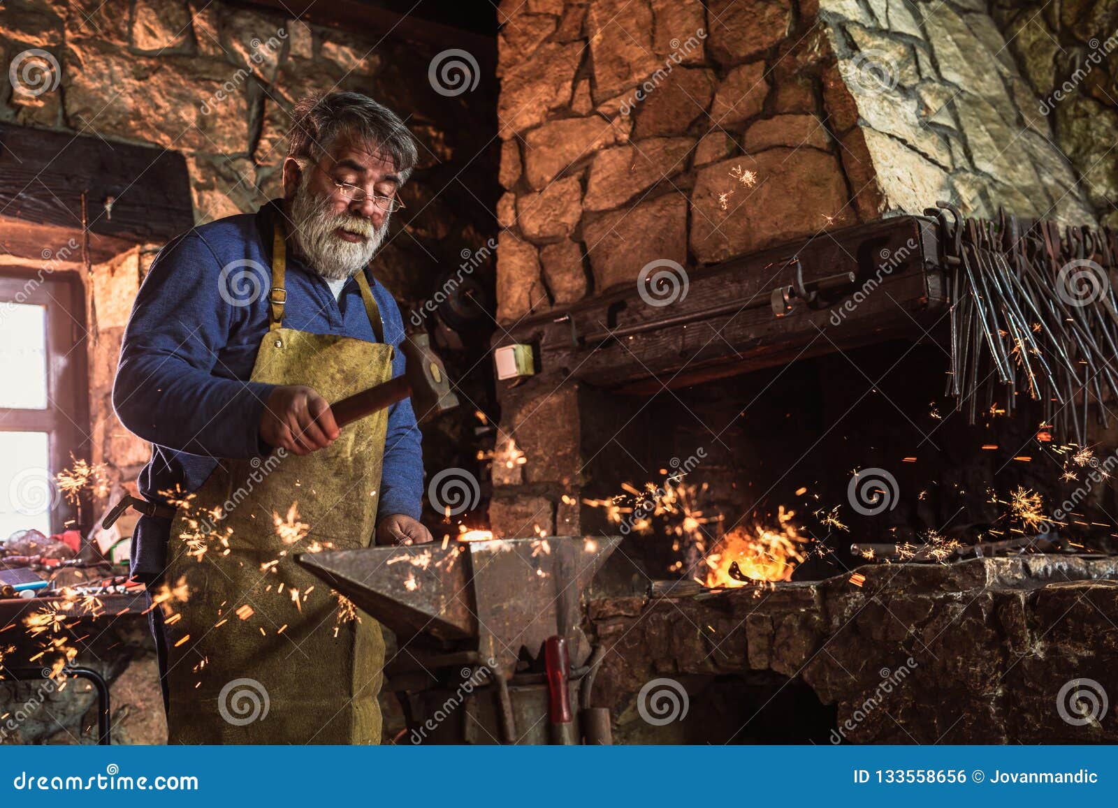 The Blacksmith Manually Forging The Red-hot Metal On The Anvil In ...