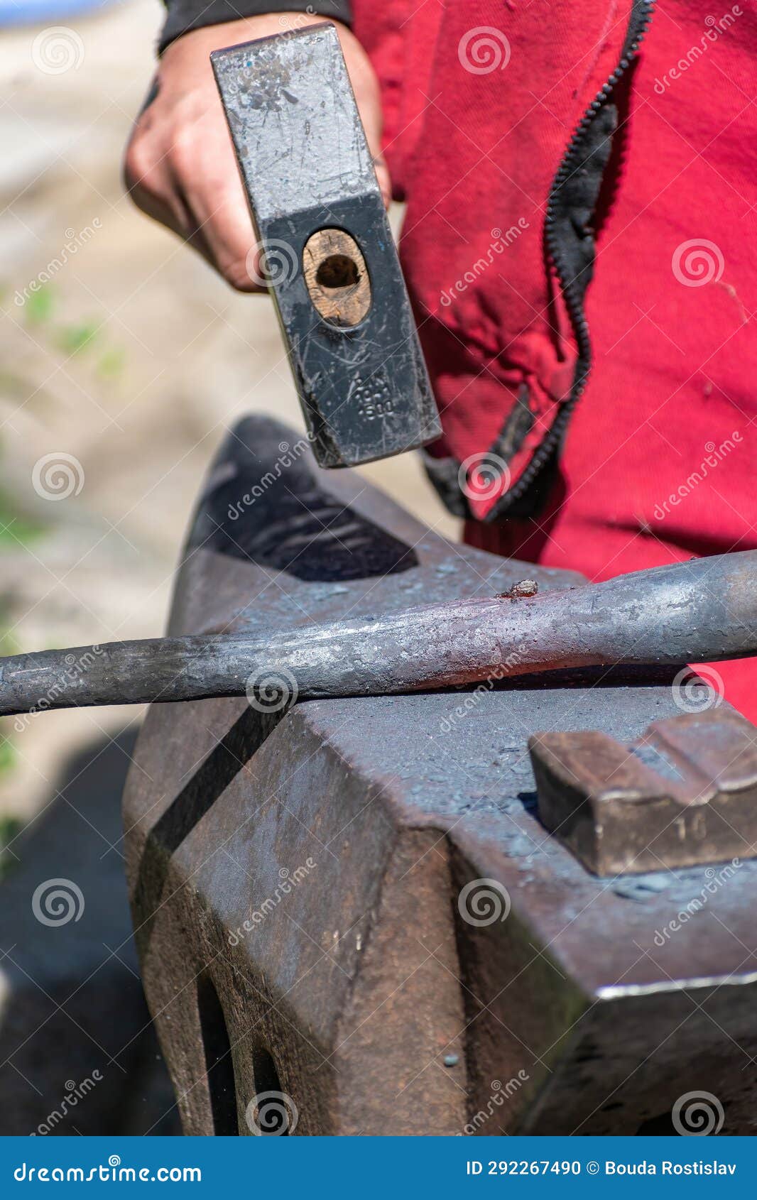 A Blacksmith Working a Piece of Iron while Working on an Anvil Stock ...