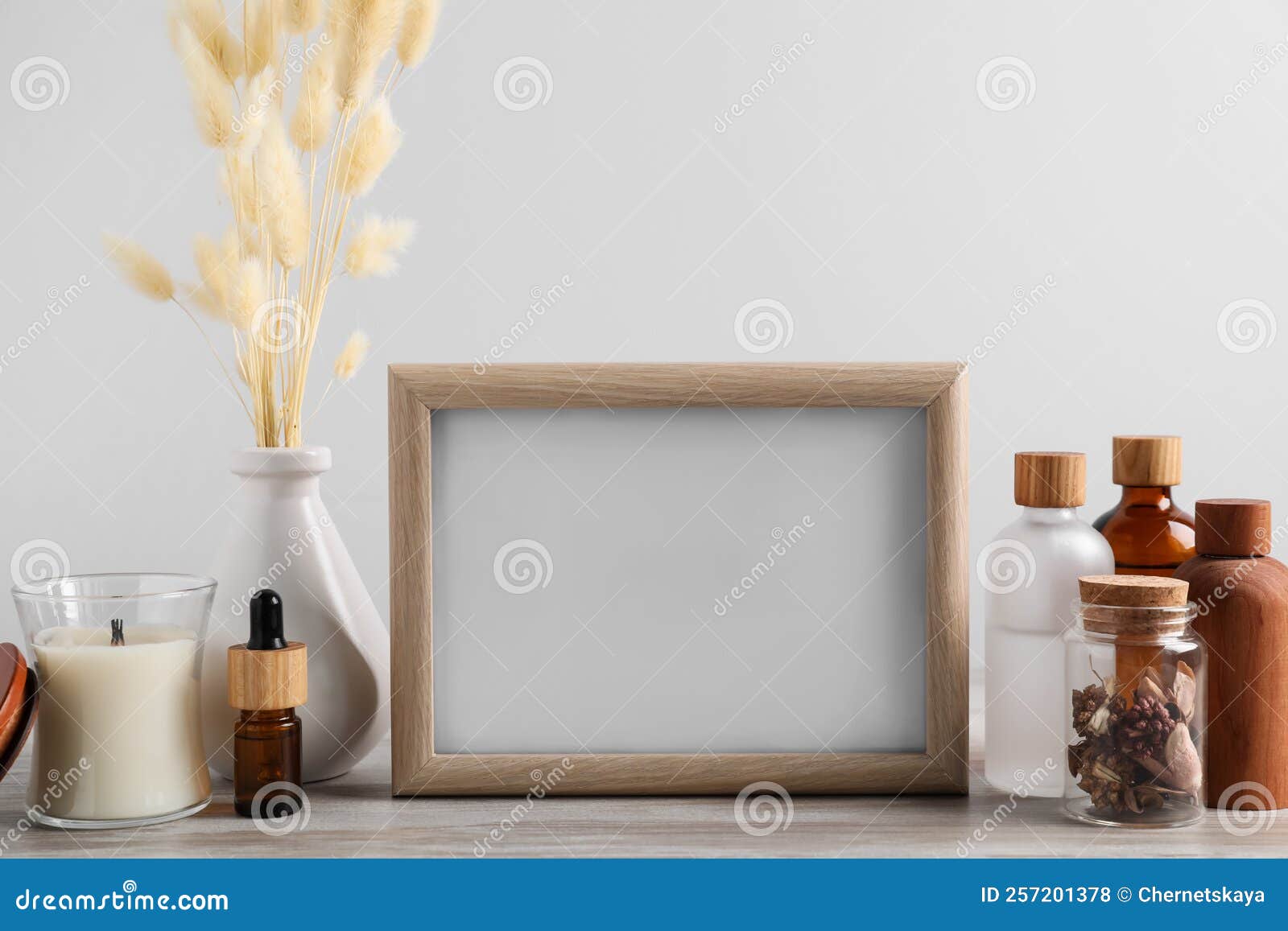 Blank Photo Frame, Different Bottles and Decor Elements on Wooden Table ...