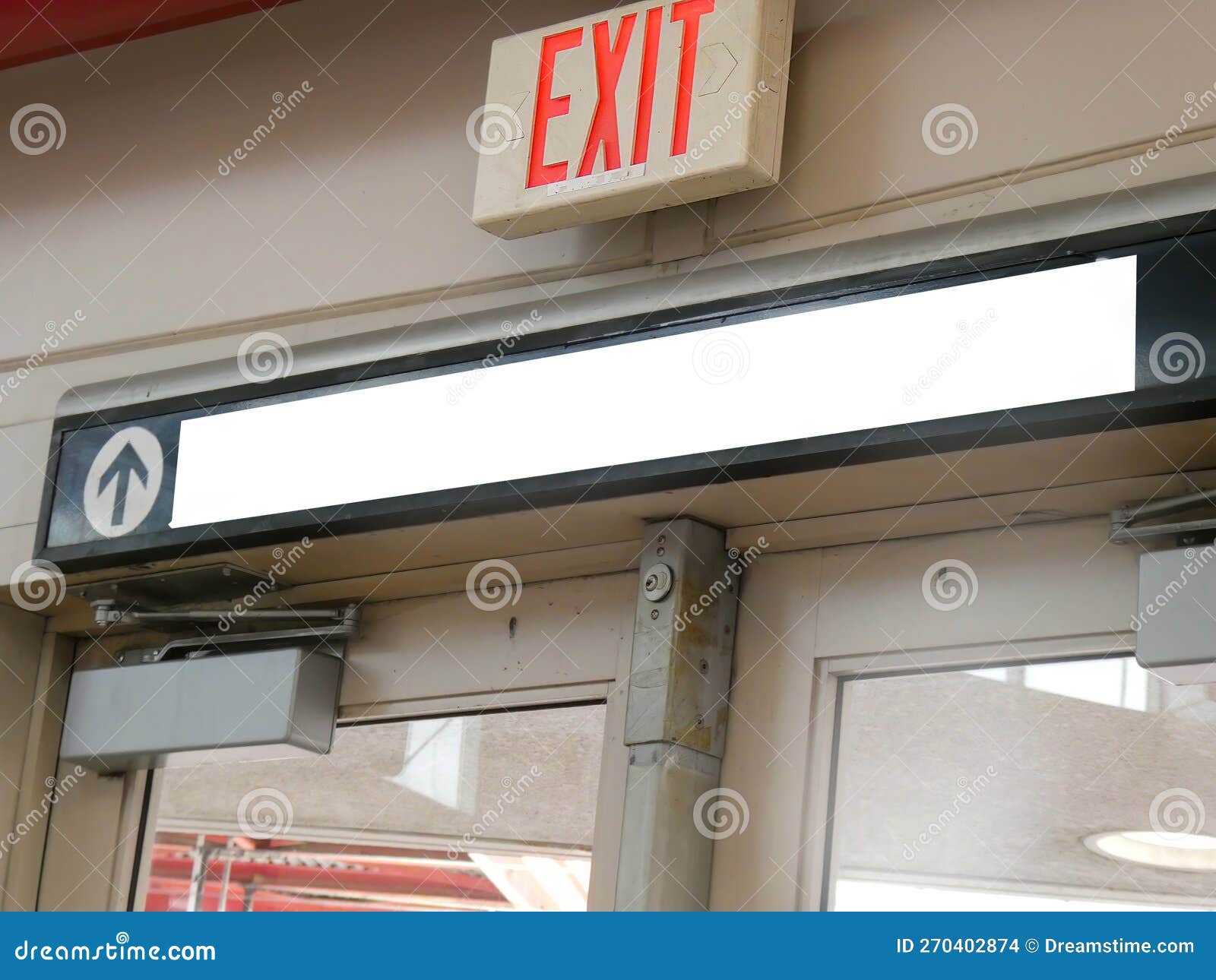 Blank White Sign with an Arrow Over a Doorway with an Orange Exit Sign ...