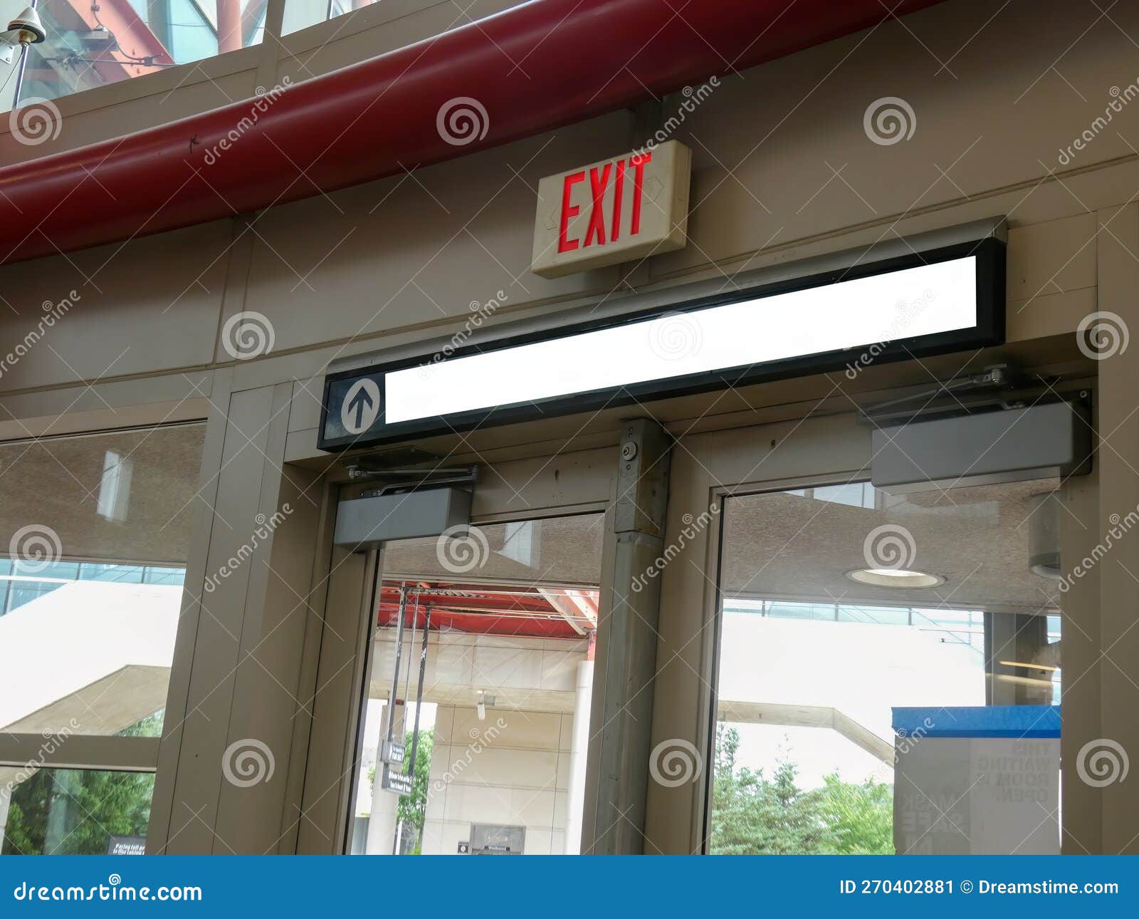Blank White Sign with an Arrow Over a Doorway with an Orange Exit Sign ...
