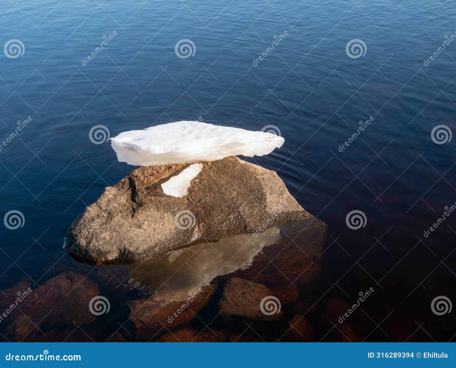 Block of Ice Melting on Rock Peaking Out of Water Stock Photo - Image ...