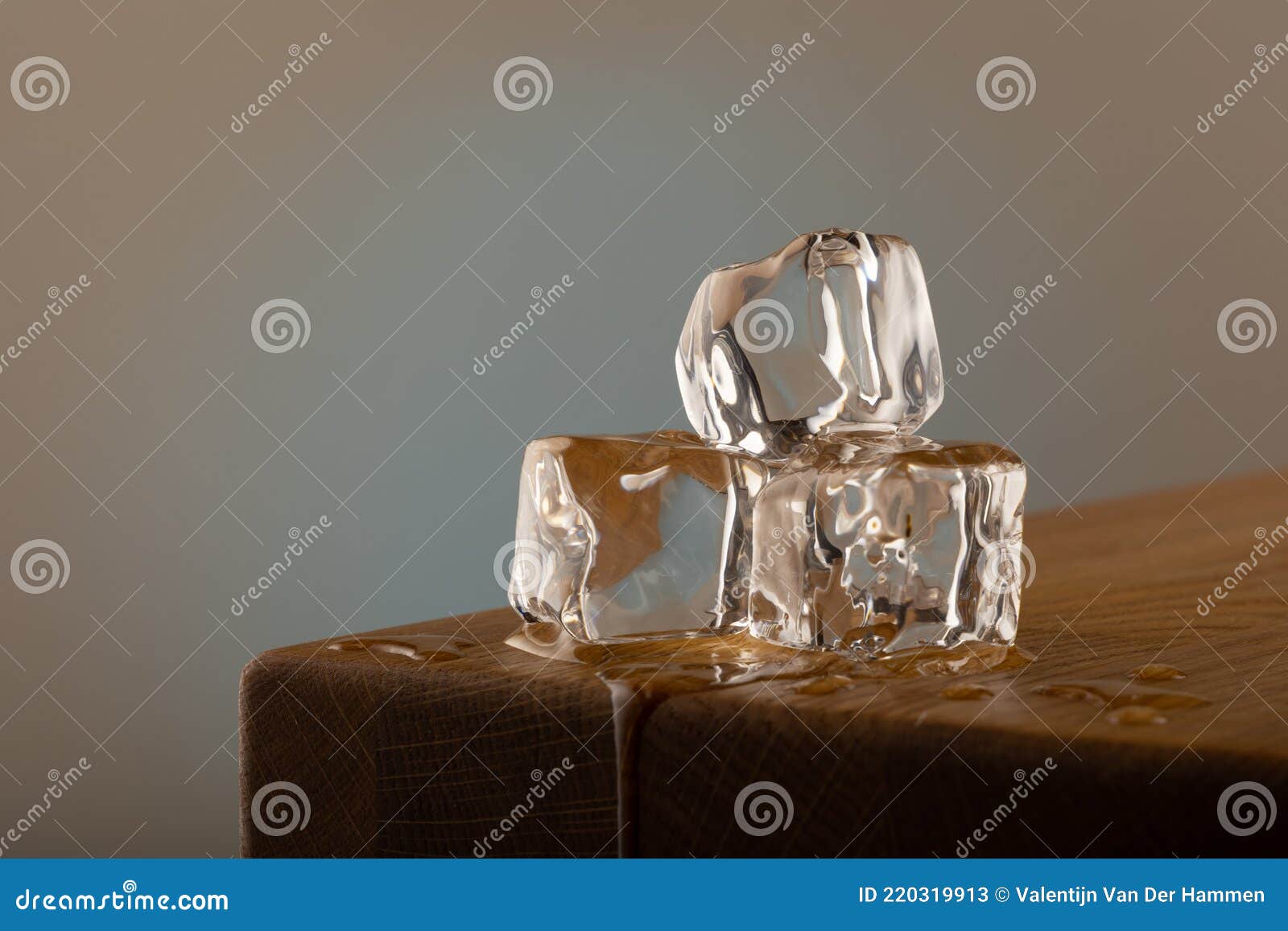 3 Blocks of Ice Melting on a Oak Table, with a Blue Shined Background ...
