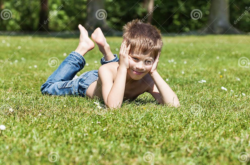 Blond boy lying on grass stock photo. Image of green - 31448924