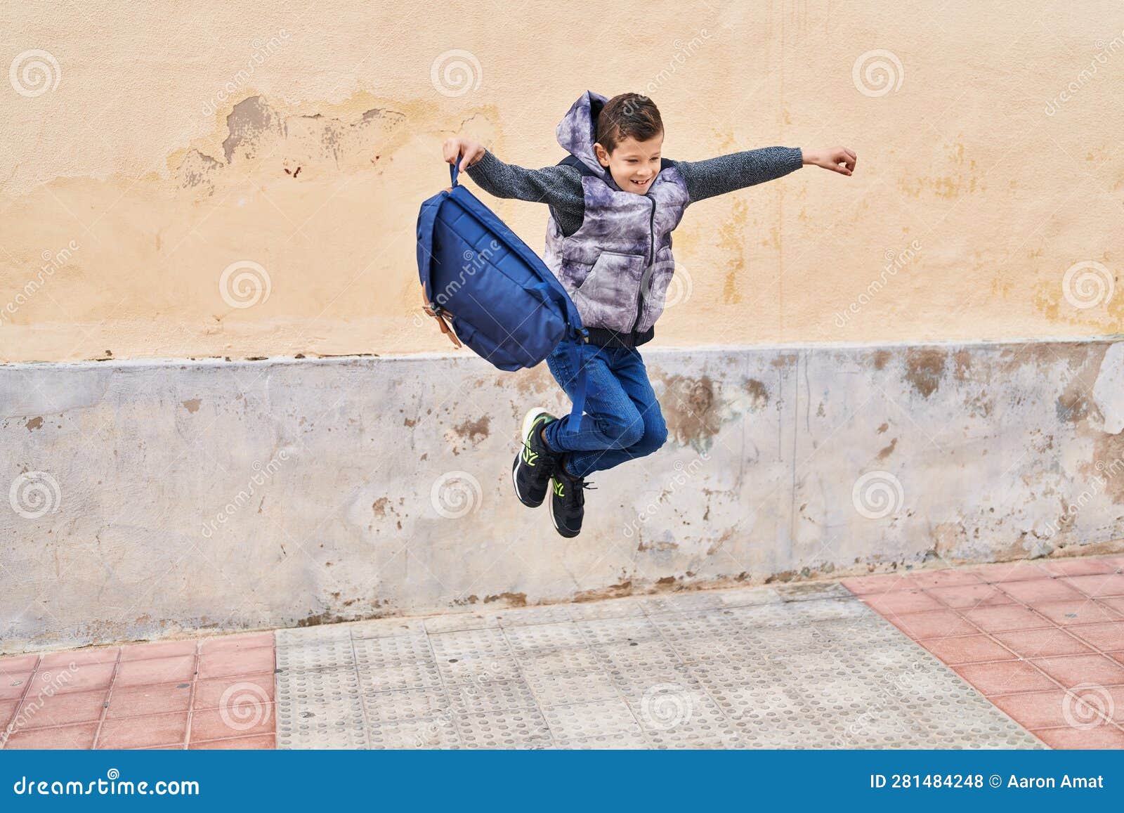 Blond Child Holding Backpack Jumping at Street Stock Photo - Image of ...