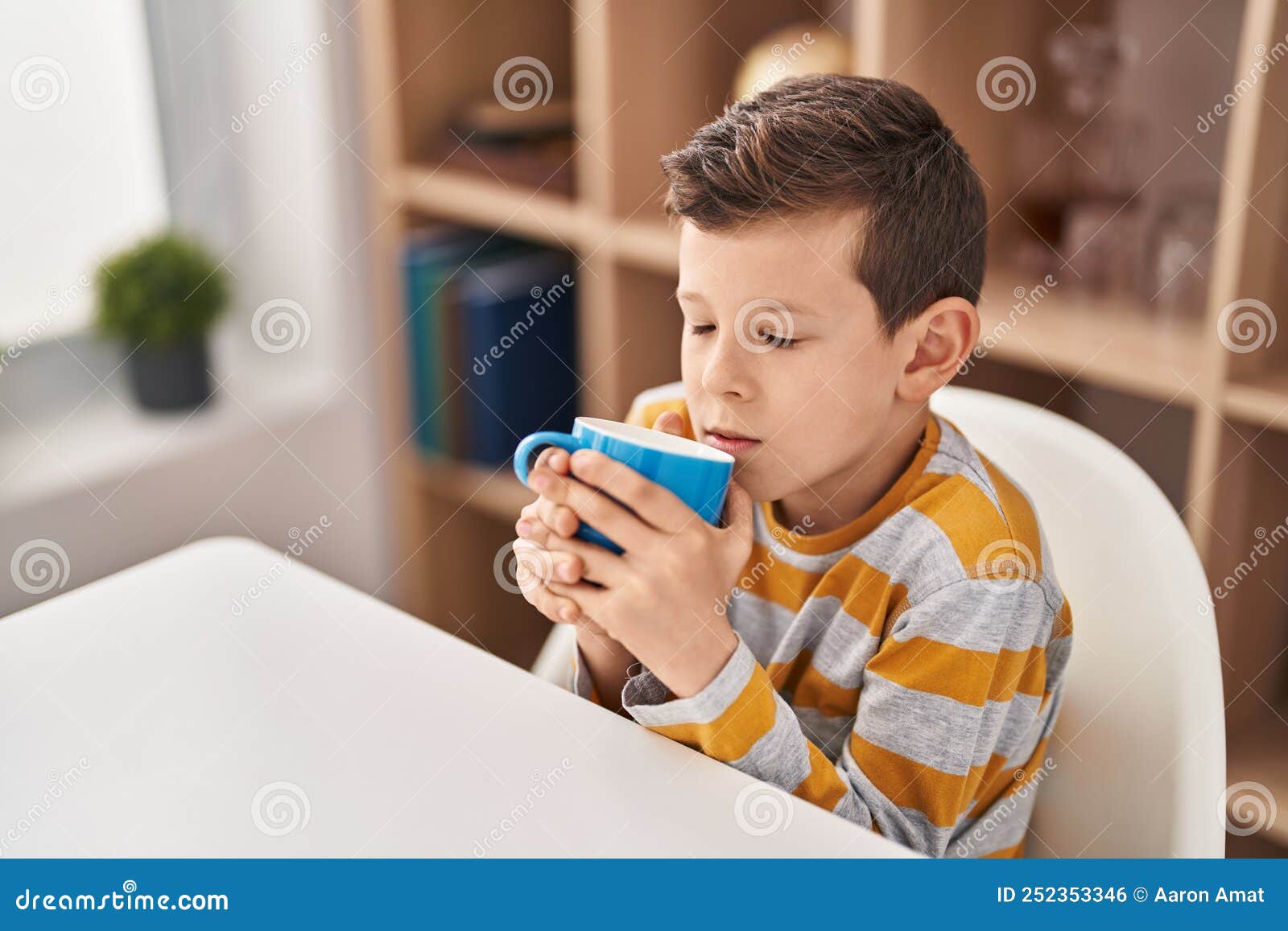 Blond Child Smelling Milk Sitting on Table at Home Stock Photo - Image ...