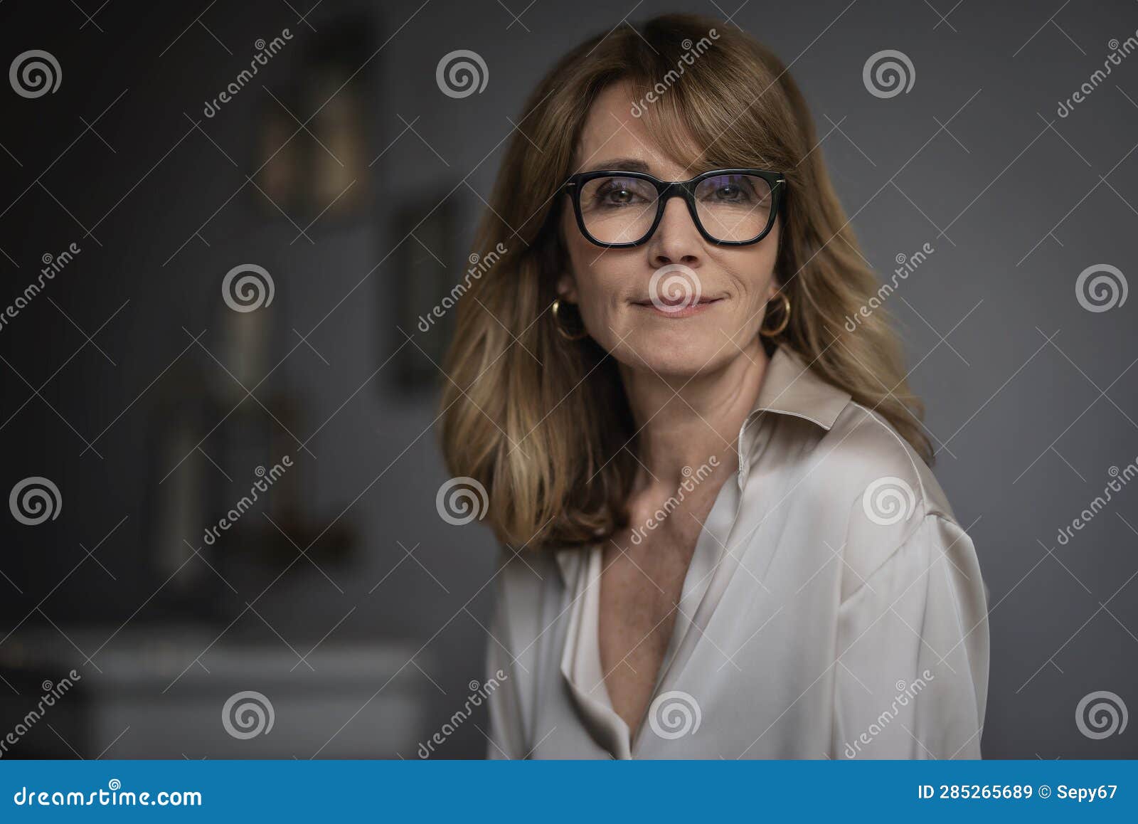 Blond Haired Mature Female Portrait With Grey Wall In The Background