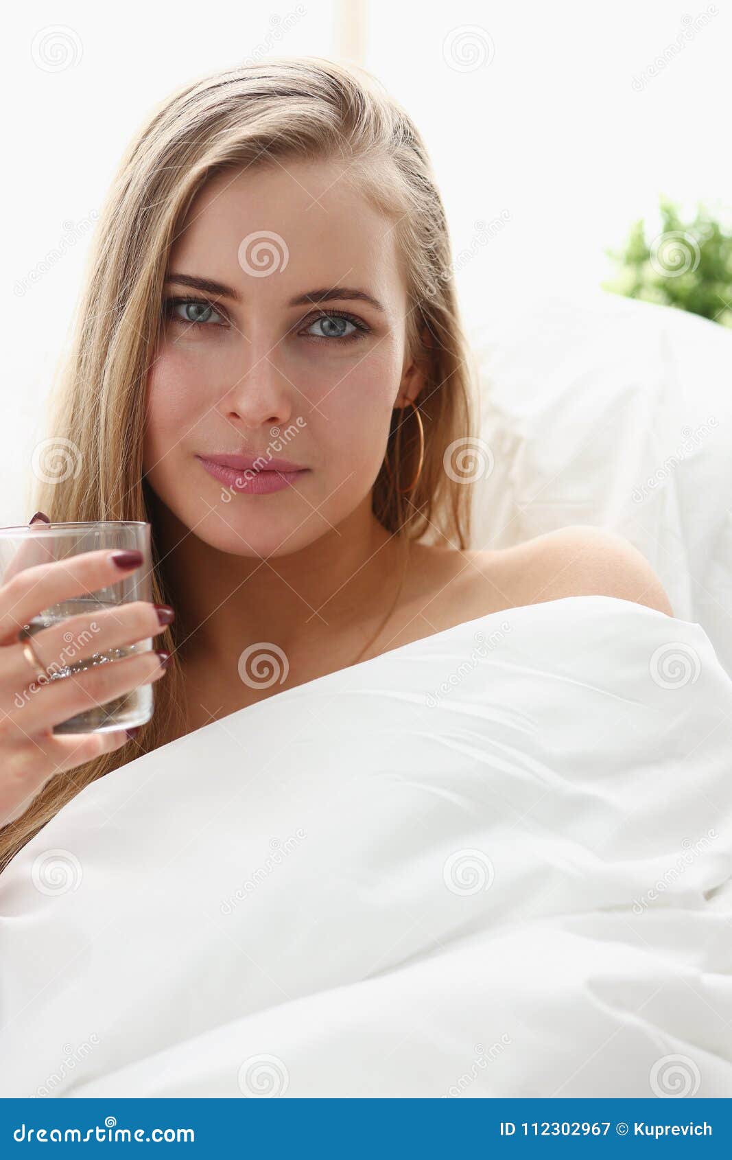 Blond Woman Hold Glass Of Water In Arm Early Morning Stay In Bed Stock