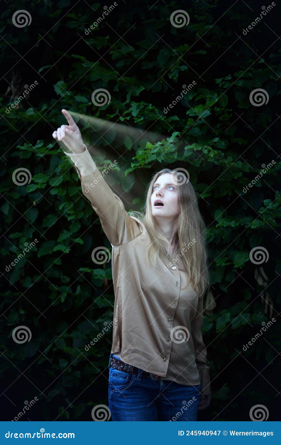 Blond Woman Standing in Nature and Pointing at a Light in Awe Stock ...