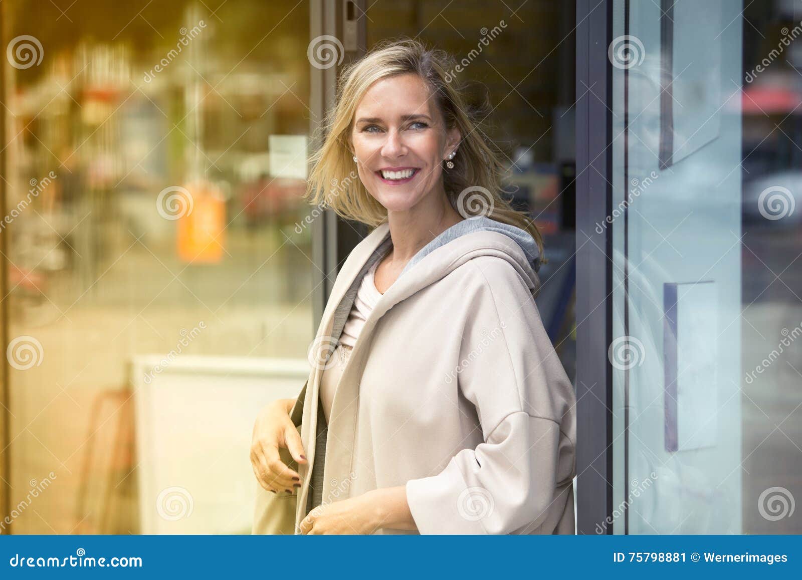Blond Woman Walking Out of a Store Stock Image - Image of coat, blonde ...